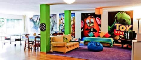 Quarto com parede verde de destaque, um sofá, um pufe azul e um grande pôster de Toy Story 3.