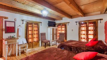 Quarto com duas camas, teto de madeira, televisão e escrivaninha com cadeira.