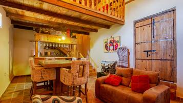 Uma sala de estar aconchegante com teto de madeira, uma área de refeições com mesa e cadeiras de madeira, e um guarda-roupa grande de madeira.
