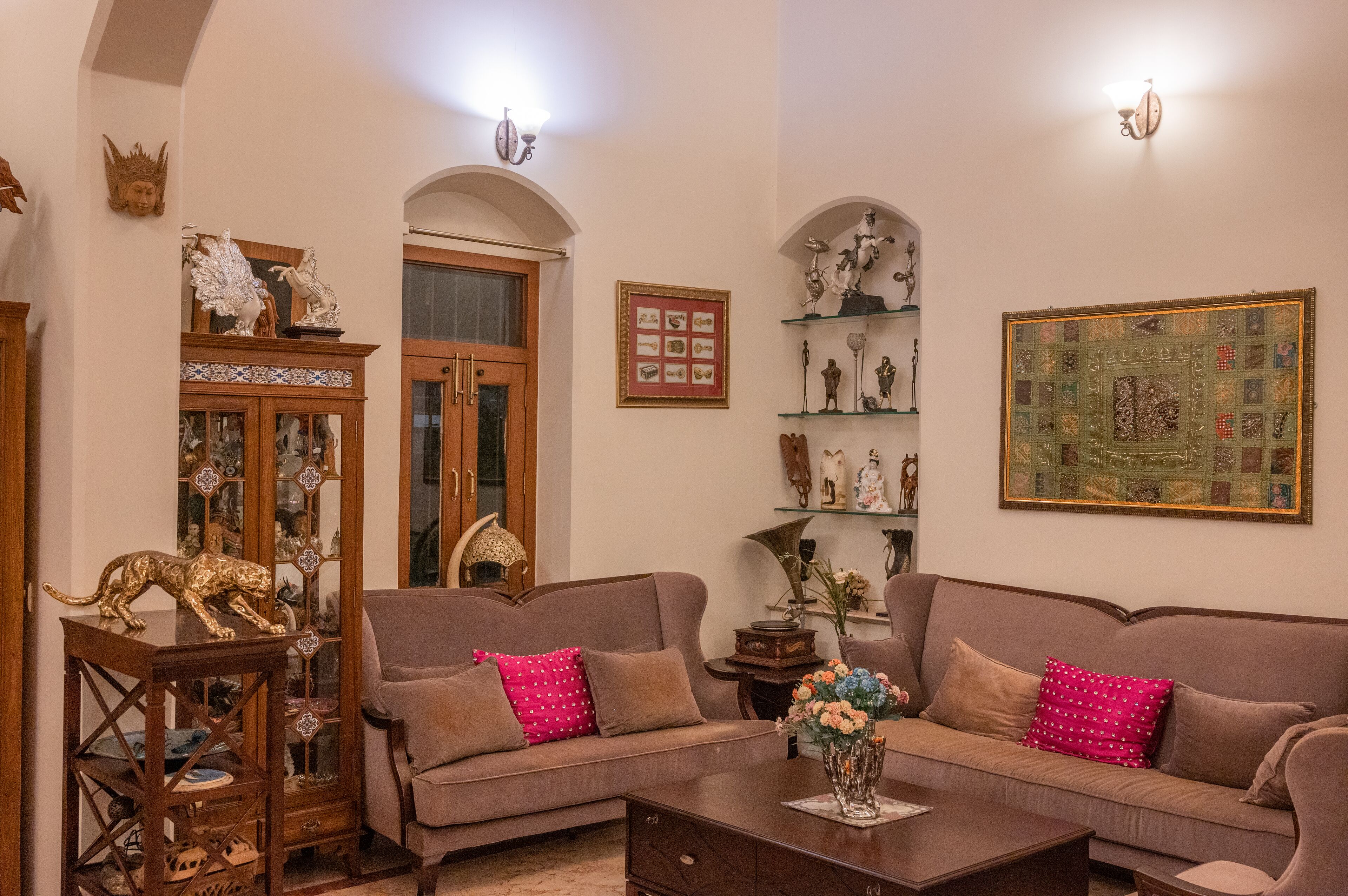 Sala de estar com um sofá marrom, um armário de madeira com portas de vidro e um objeto decorativo na parede.