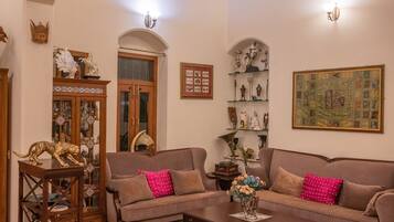 Sala de estar com um sofá marrom, um armário de madeira com portas de vidro e um objeto decorativo na parede.