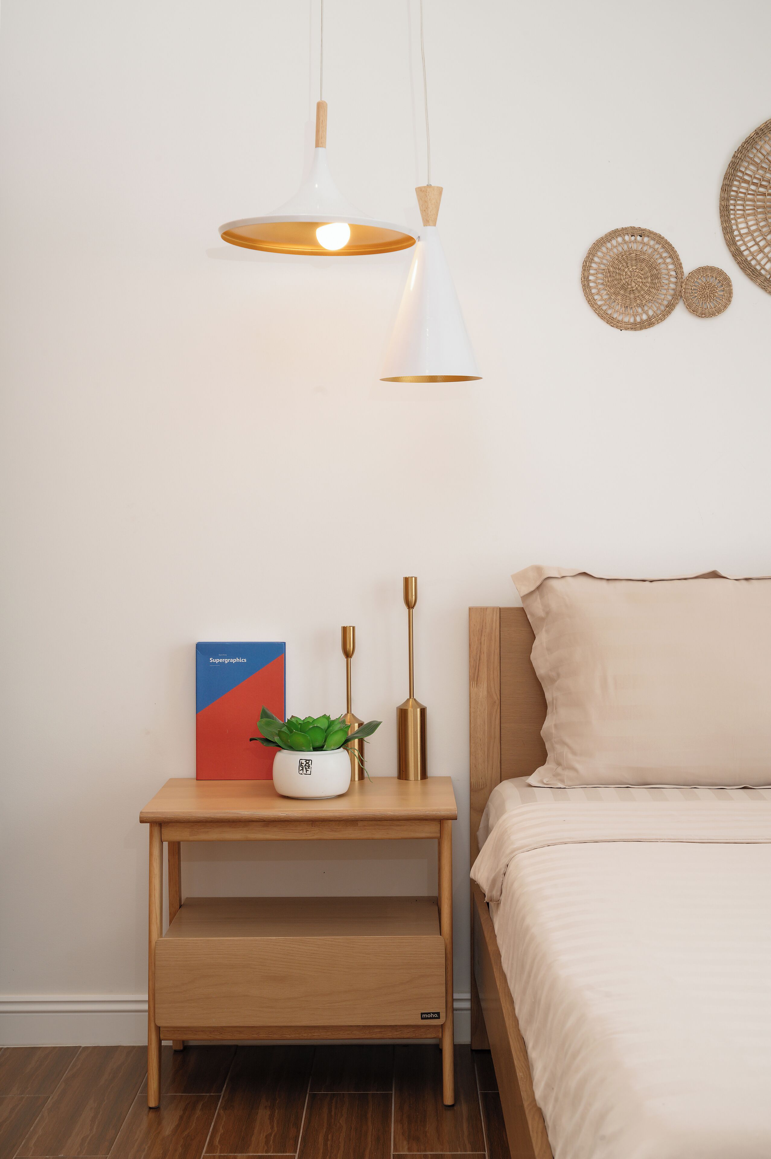 Quarto bem arrumado com cama, mesa de cabeceira e duas luminárias pendentes.