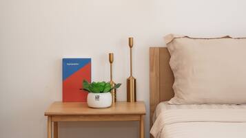 Quarto bem arrumado com cama, mesa de cabeceira e duas luminárias pendentes.