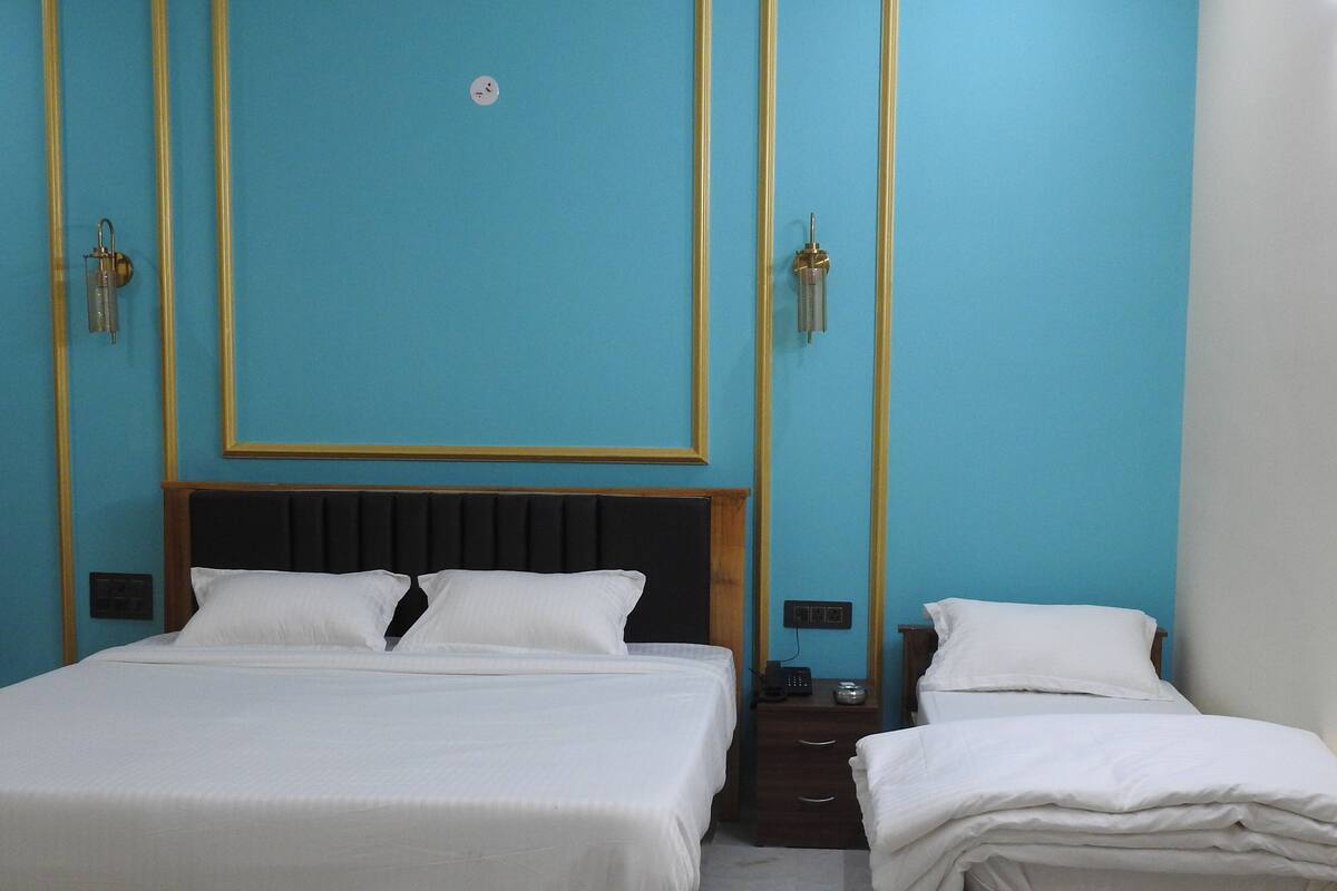 Quarto com duas camas, cabeceira de madeira e parede azul com detalhes dourados.