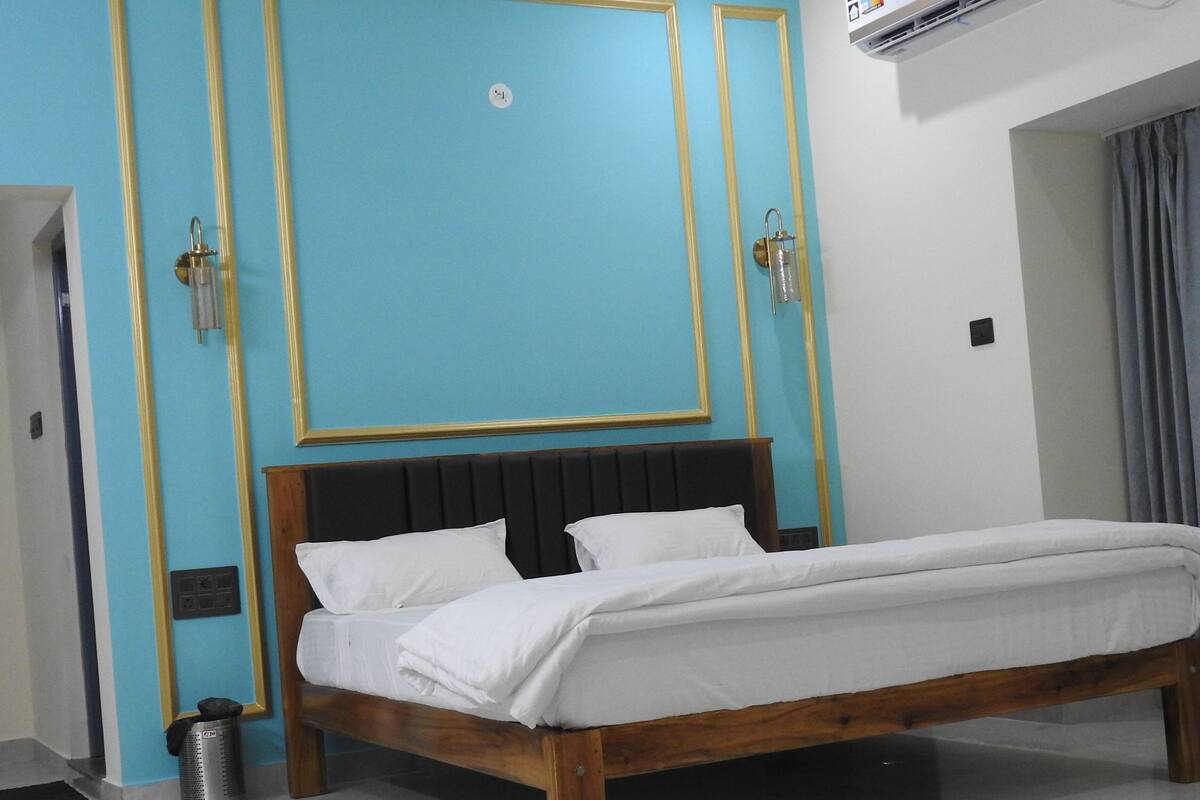 Quarto com cama, ar condicionado fixado na parede e uma porta.