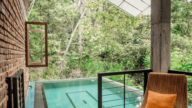 Área de piscina com uma cadeira e vista para paisagem natural.