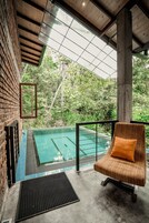 Área de piscina com uma cadeira e vista para paisagem natural.