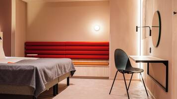 Quarto moderno com cama, um banquinho vermelho, escrivaninha e espelho.