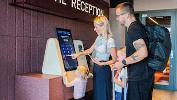 Uma área de recepção com um quiosque de check-in digital e uma placa que diz THE RECEPTION.