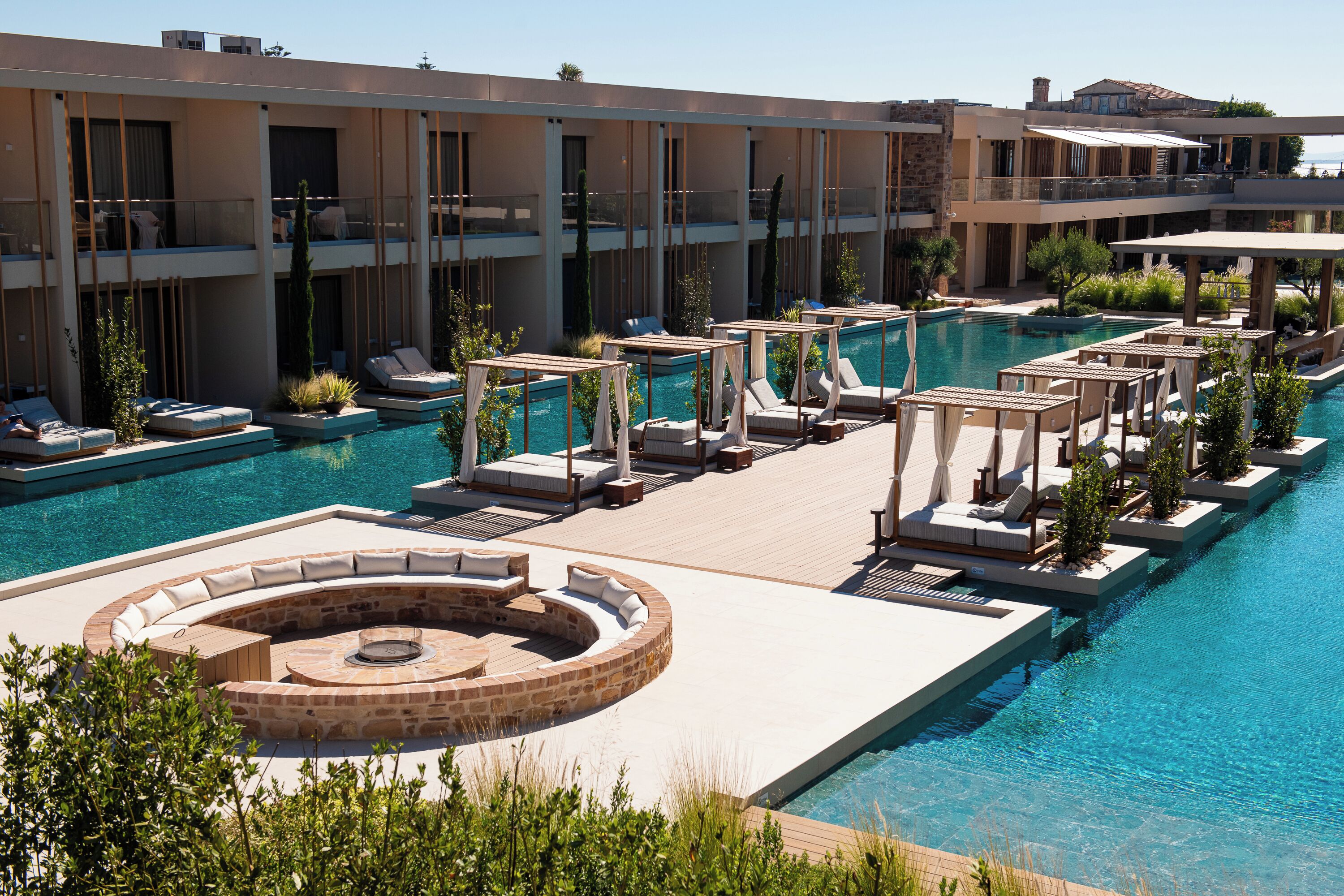Um resort com uma piscina grande, espreguiçadeiras e um espaço de estar circular.