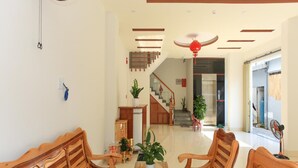 Uma sala de estar espaçosa com móveis de madeira, uma mesa de centro de vidro e uma escada que leva a um andar superior.