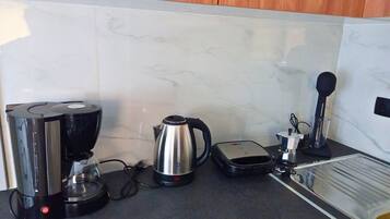 Uma cozinha com cafeteira, chaleira, torradeira e liquidificador na bancada.