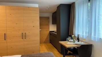 Quarto moderno com cama, mesa de jantar com cadeiras, área de cozinha e um guarda-roupa espaçoso.