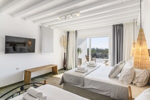 Quarto de hotel moderno com duas camas, um banco, uma TV e varanda com vista.