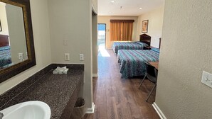 Quarto de hotel com banheiro, duas camas, um espelho grande e vista para o exterior.