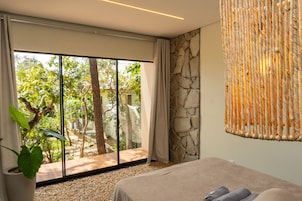 Quarto moderno com uma grande janela, parede de pedra e luminária pendente.