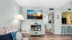 Uma sala de estar com sofá, luminária, televisão fixada na parede e estante.
