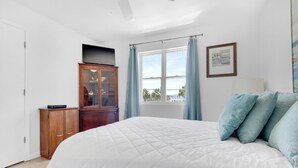 Quarto com uma cama grande, um armário de madeira, uma janela com cortinas e um ventilador de teto.