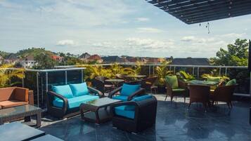 Terraço no telhado com móveis de exterior, incluindo sofás e cadeiras, e uma mesa de vidro.