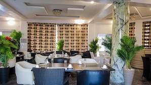 Restaurante com interior moderno, apresentando colunas de mármore, papel de parede estampado e assentos confortáveis.