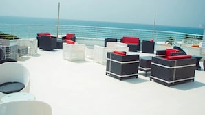 Terraço no telhado com área de estar ao ar livre e vista para o mar.