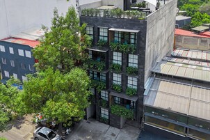 Um edifício com várias andares, varandas, janelas amplas e uma árvore na frente.