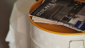 Um recipiente branco com padrão Louis Vuitton, contendo revistas e uma xícara de café.