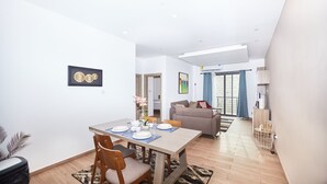 Uma sala de estar moderna com área de jantar, com sofá, mesa de centro e mesa de jantar posta com pratos e cadeiras.