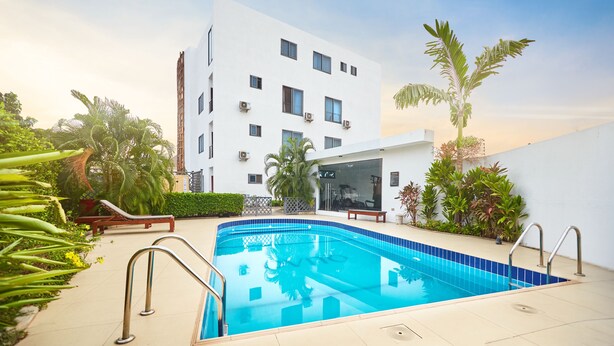 Um hotel moderno com piscina, rodeado por vegetação exuberante e palmeiras.