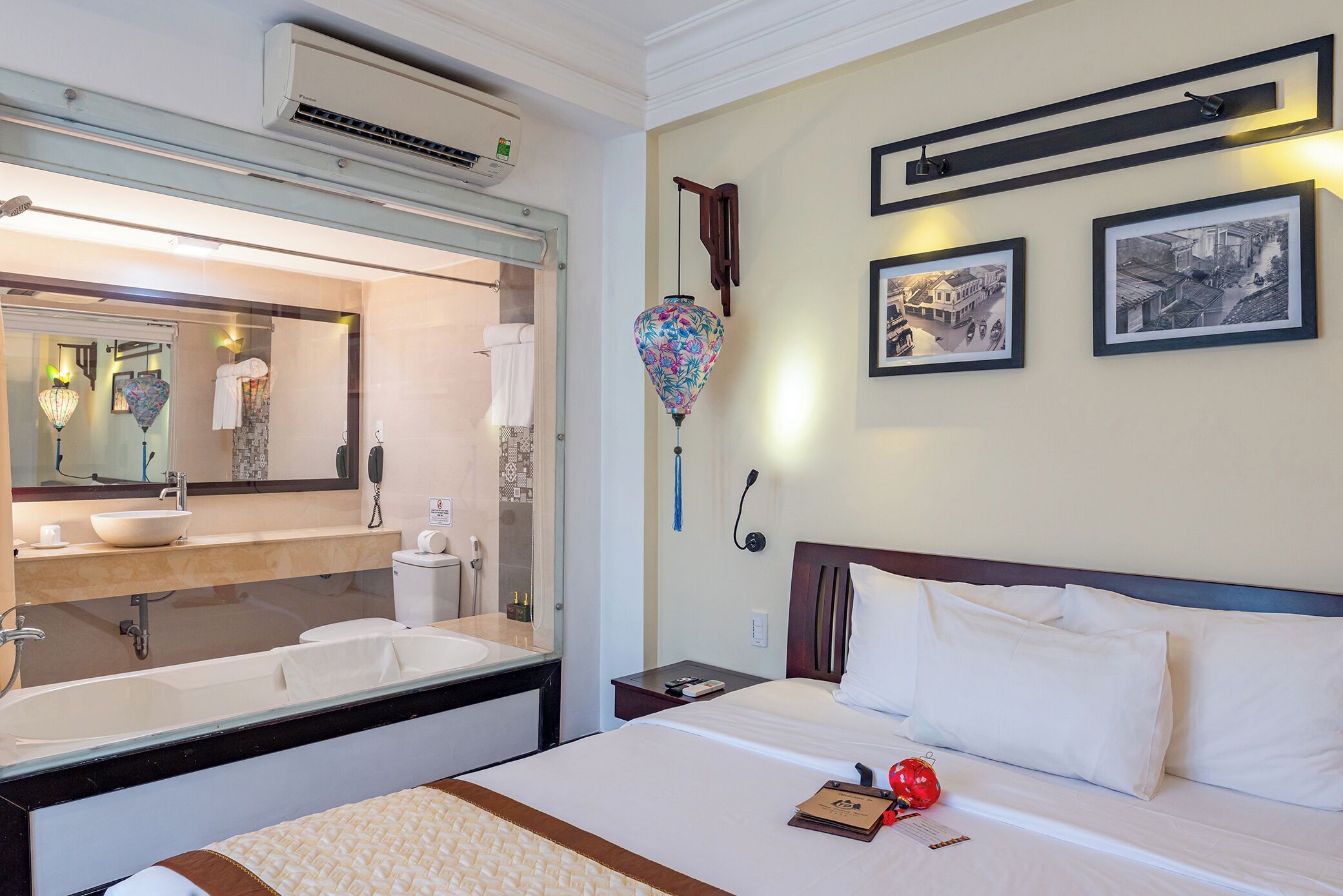 Quarto de hotel com uma cama grande, pia dupla, espelho e duas quadros na parede.