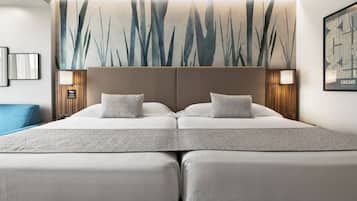 Quarto de hotel com uma cama grande, duas mesas de cabeceira, cabeceira com painel de plantas e um mapa emoldurado na parede.
