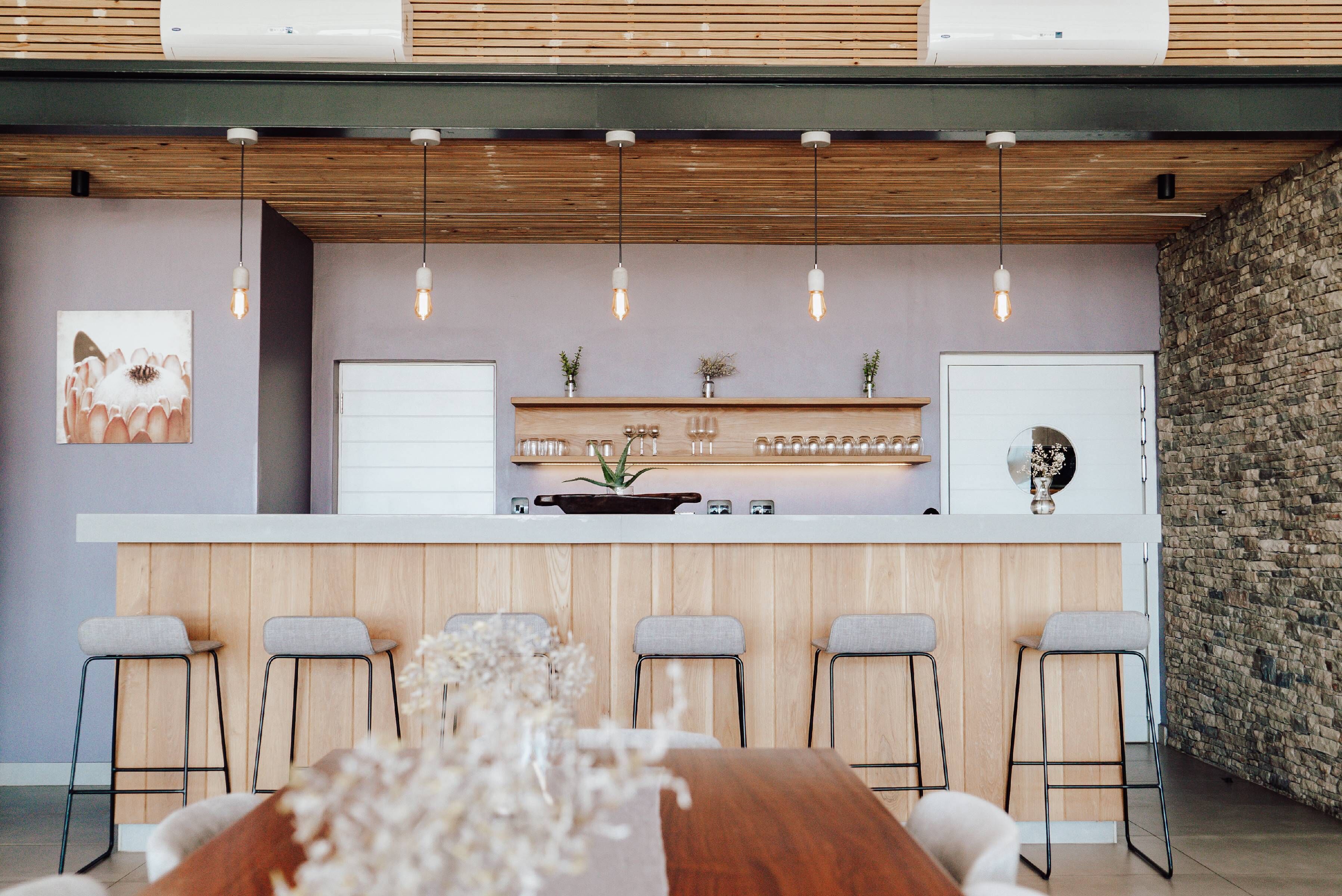 Cozinha moderna com área de bar em madeira, luminárias pendentes e banquetas.