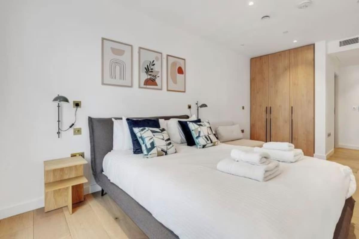 Quarto moderno com uma cama grande, luminárias de cabeceira e obras de arte na parede.