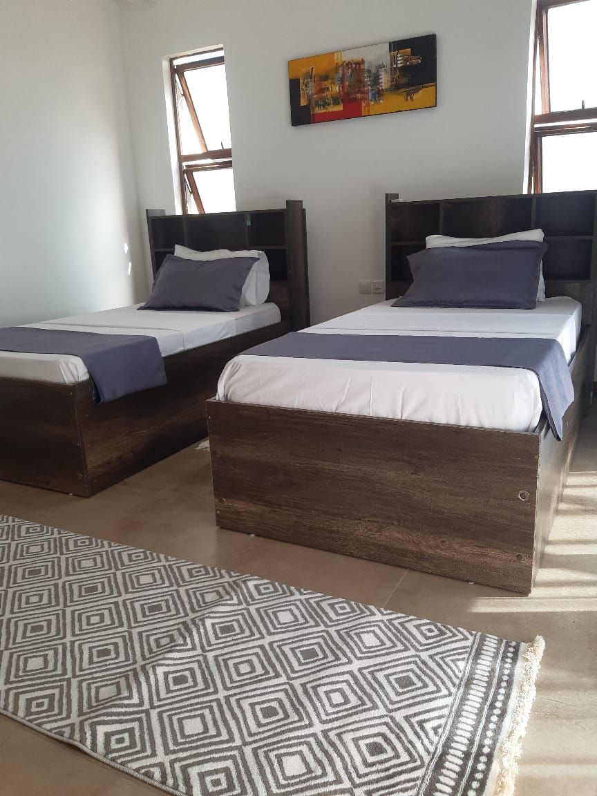 Quarto com duas camas, um tapete estampado e um quadro na parede.