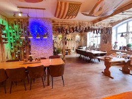 Um restaurante com interior rústico, apresentando uma parede de tijolos, teto de madeira e diversos objetos pendurados.