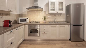 Uma cozinha moderna com eletrodomésticos de aço inoxidável, armários brancos e piso de madeira.