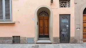 Um edifício com porta dupla de madeira, pequena entrada em arco e porta com grafite.