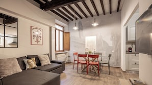 Uma sala de estar aconchegante, com um sofá, uma mesa de jantar com cadeiras e uma área de cozinha.