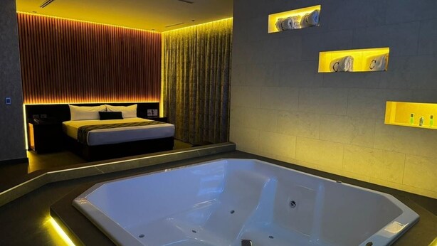 Um spa moderno com uma banheira grande, uma cama e chuveiro fixado na parede.