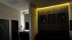 Um hall de hotel moderno com uma mesa de recepção, um sofá e obras de arte emolduradas na parede.