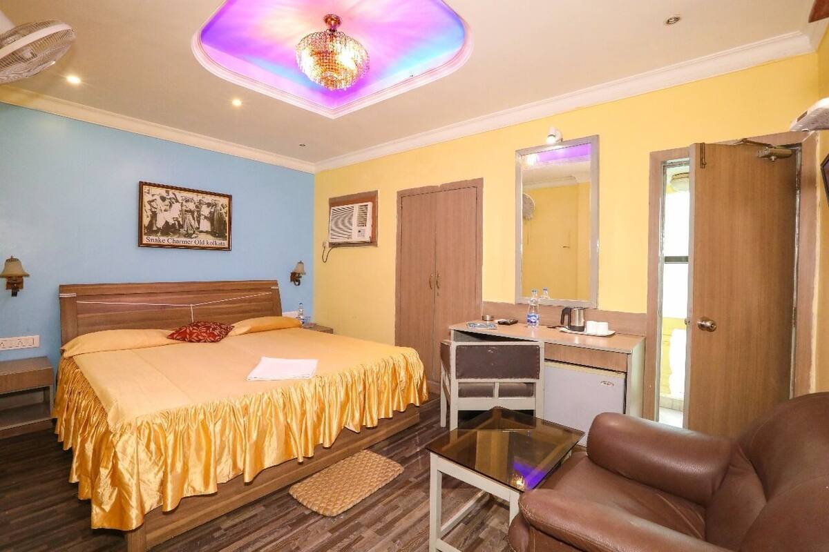 Quarto de hotel com cama, escrivaninha, cadeira e espelho.