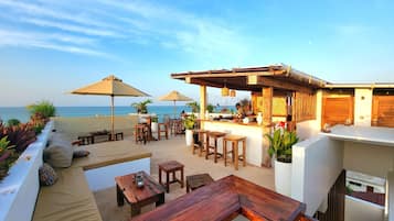 Um terraço à beira-mar com área de estar ao ar livre, bar e vista para o oceano.