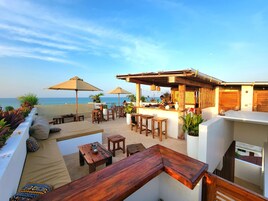Um terraço à beira-mar com área de estar ao ar livre, bar e vista para o oceano.