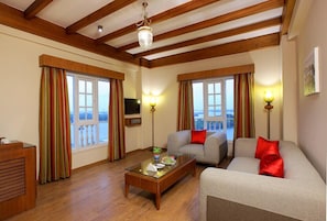 Uma sala de estar com vigas de madeira, um sofá, uma mesa de centro e uma televisão.