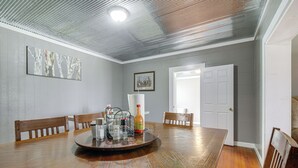 Uma área de jantar com uma mesa de madeira, cadeiras, um arranjo redondo no centro da mesa e um teto com textura.