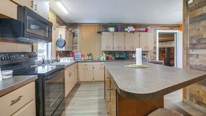 Uma cozinha com bancada de granito, eletrodomésticos de aço inoxidável, armários de madeira e parede decorativa em madeira.