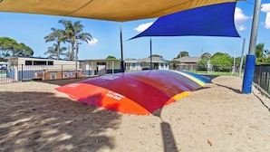 Um parquinho com um caixa de areia e áreas com sombra.
