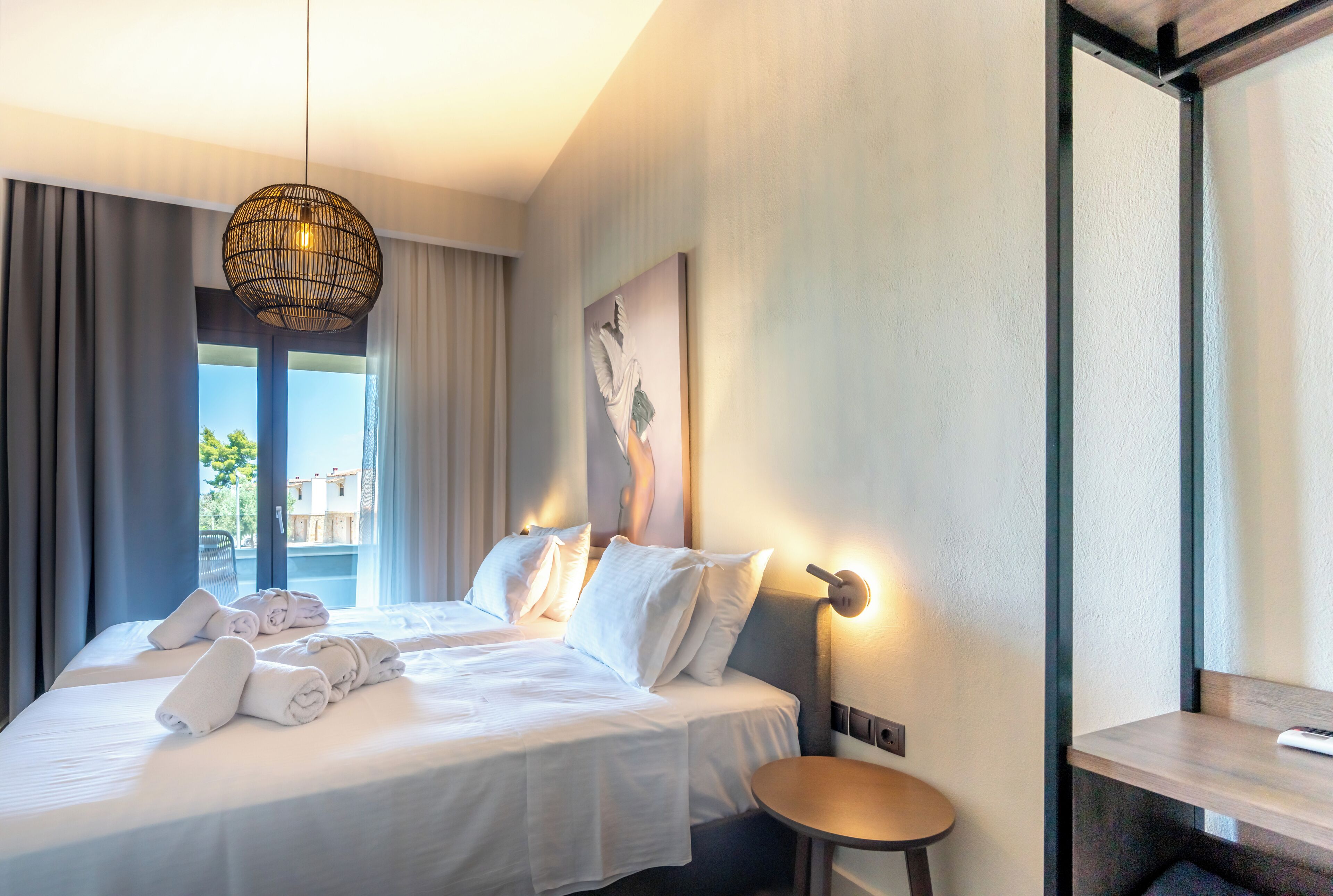 Quarto de hotel com uma cama grande, uma mesa redonda e vista para o exterior.