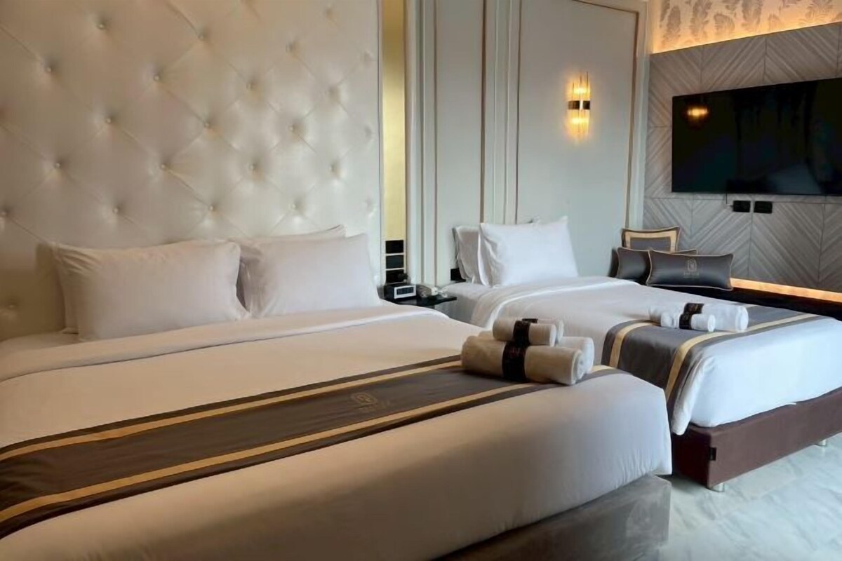 Quarto de hotel com uma cama grande, televisão fixada na parede e design moderno.