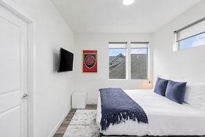 Quarto com cama, televisão, janela e radiador.